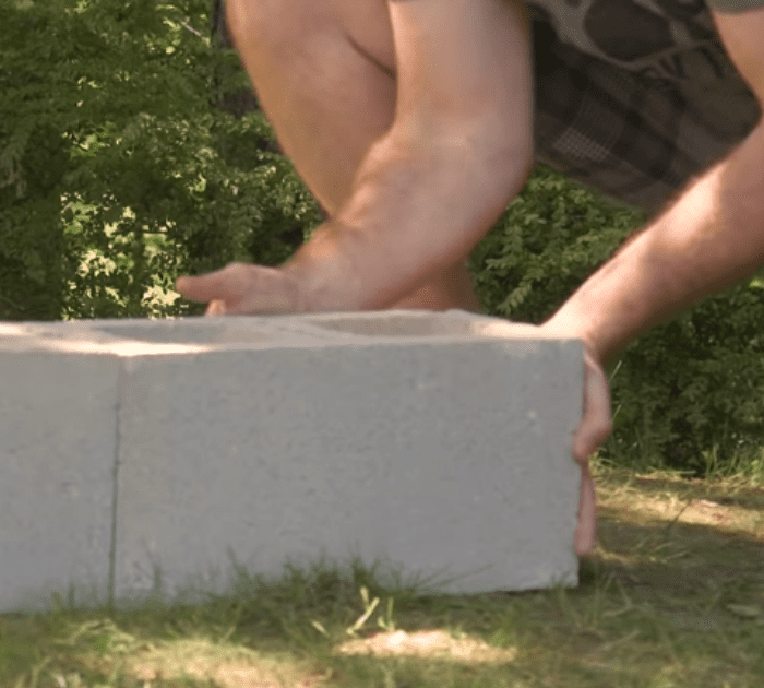 Man stacks cinder blocks then adds one more item to make modern bench ...