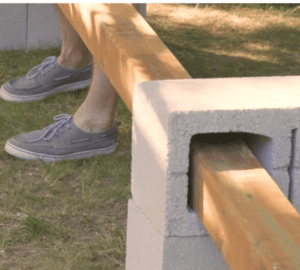 Man stacks cinder blocks then adds one more item to make modern bench ...
