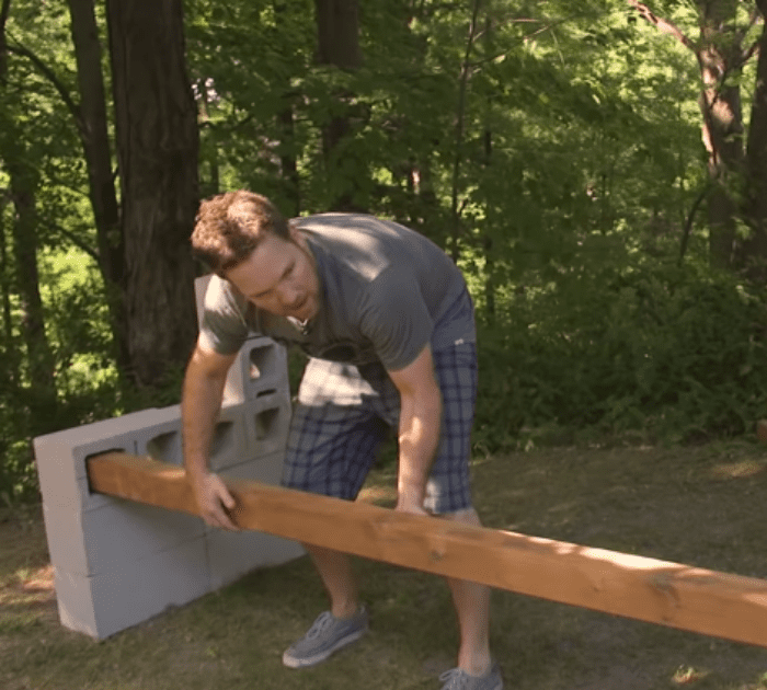 Man stacks cinder blocks then adds one more item to make modern bench ...