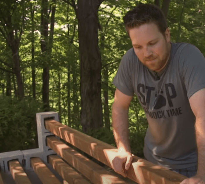 Man stacks cinder blocks then adds one more item to make modern bench ...
