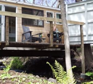 Man builds genius home out of shipping container that sits over a stream